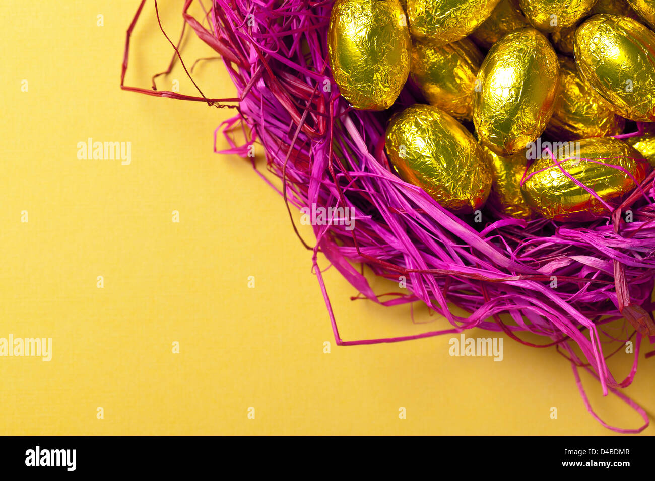 Gold easter eggs in pink nest. Holiday background with sweets. Top view ...