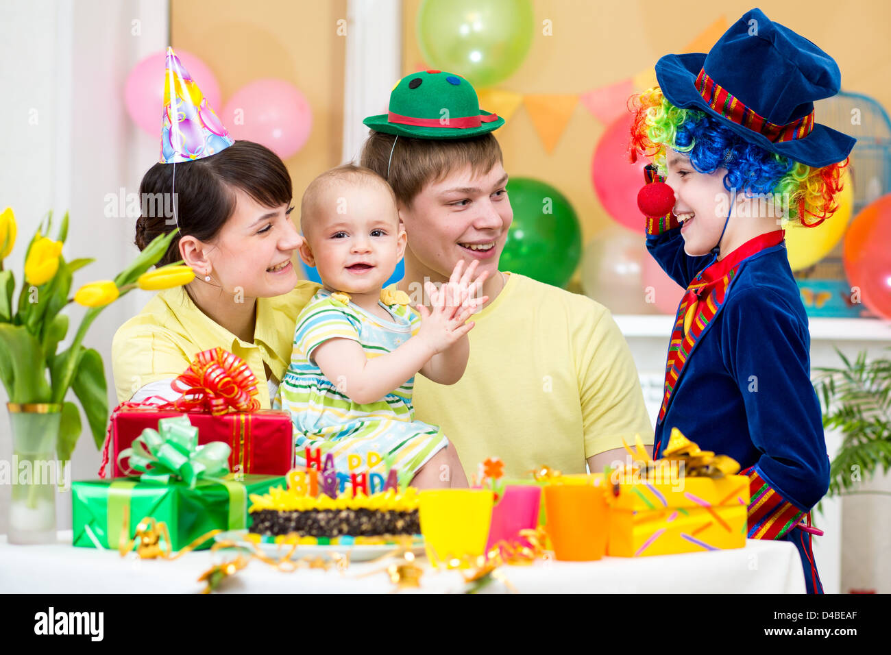 baby girl celebrating first birthday with parents and clown Stock Photo ...