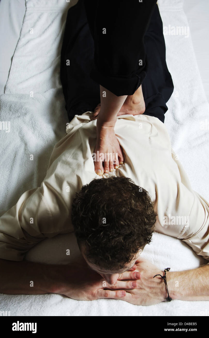 Masseuse carefully steps on her clients back applying pressure to ...