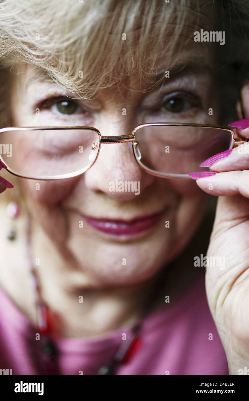 Portrait of elderly woman adjusting reading glasses Stock Photo - Alamy