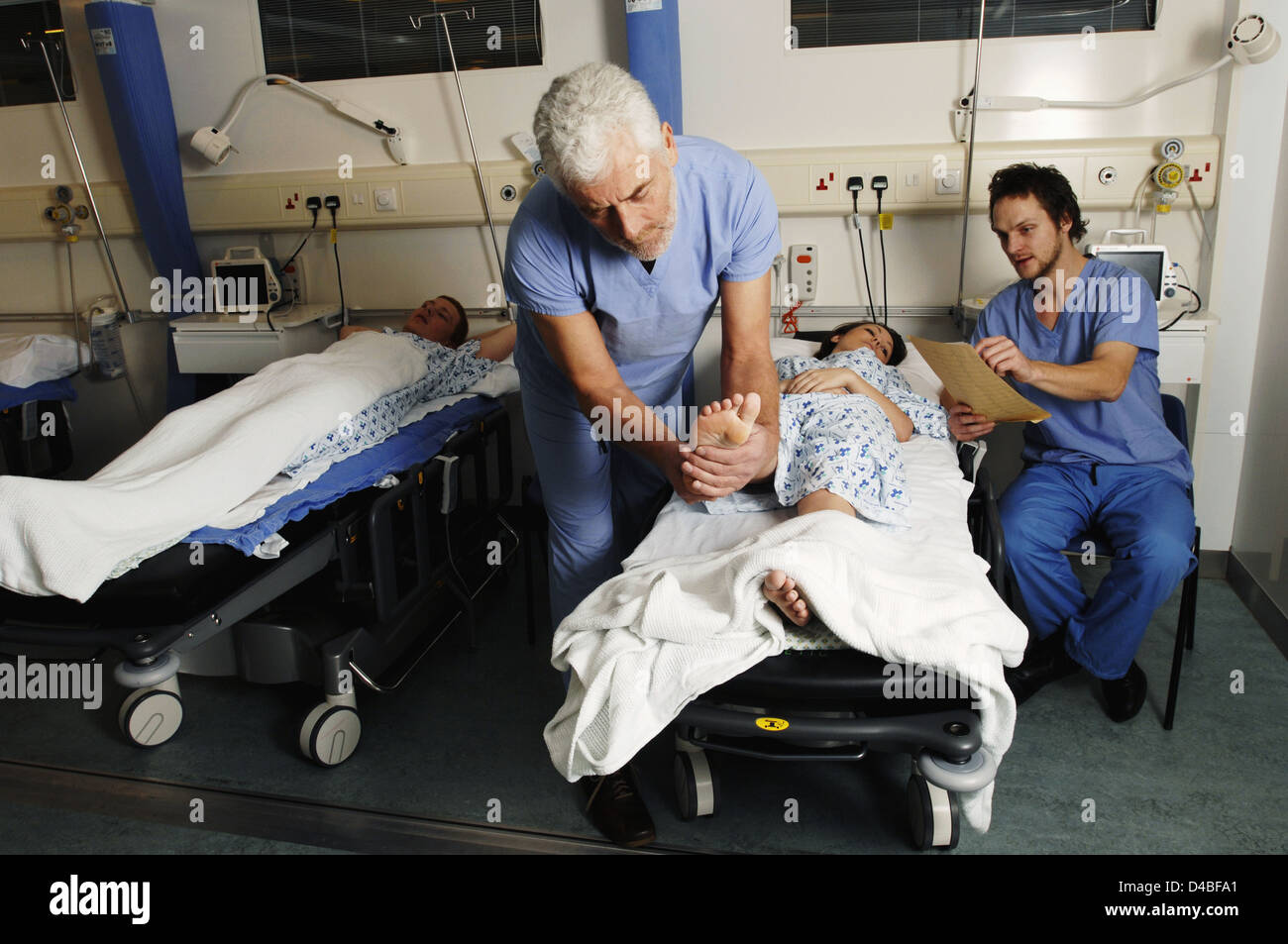 Bearded surgeon and one of his surgical team are checking female ...