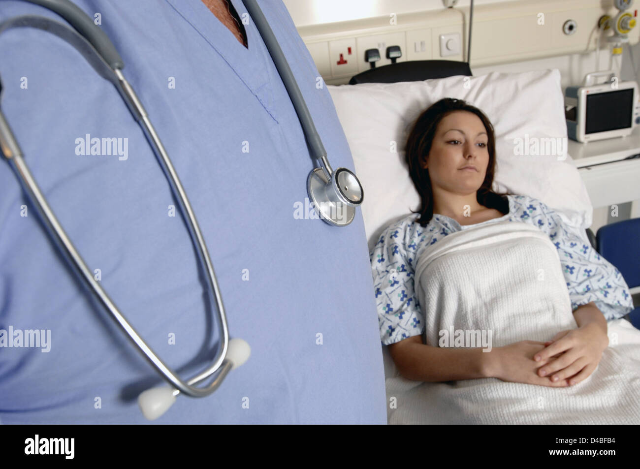 Doctor, with stethoscope around his neck stands in front of patient ...