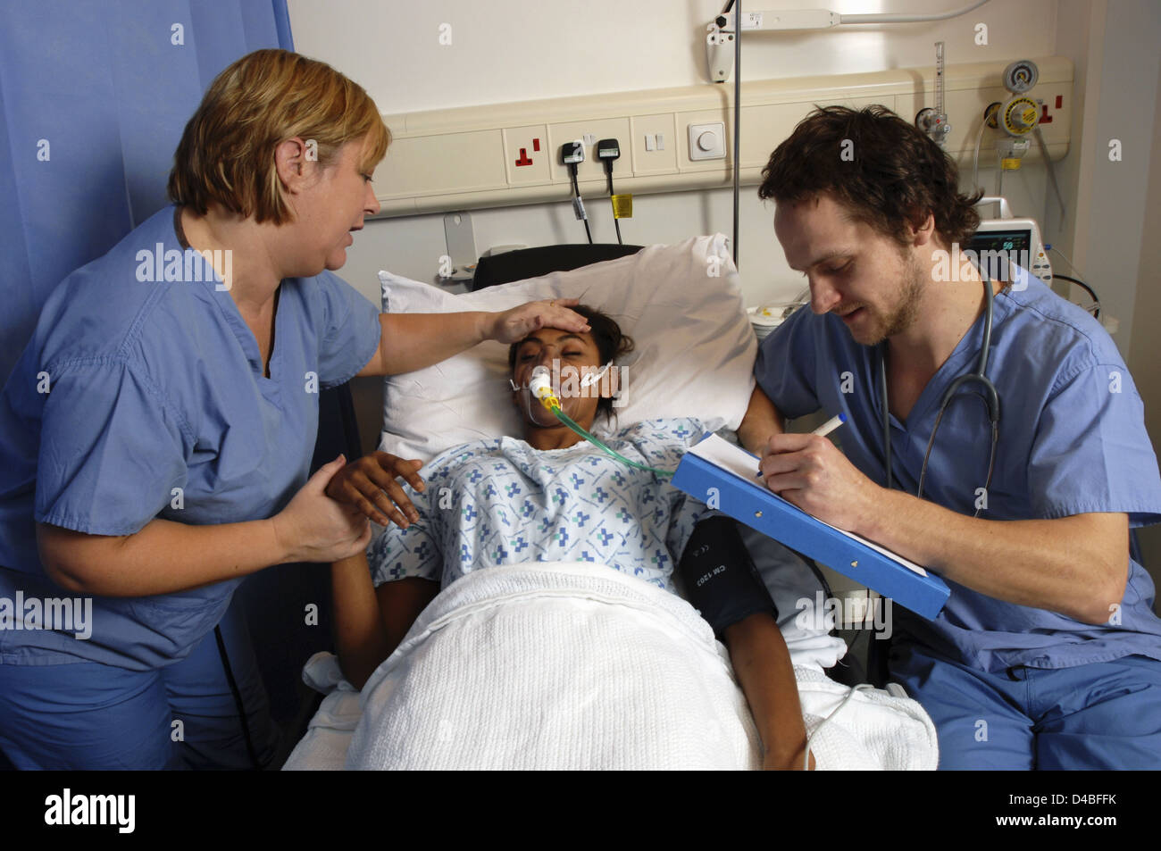 Doctor and nurse on ward rounds checking condition of young woman ...