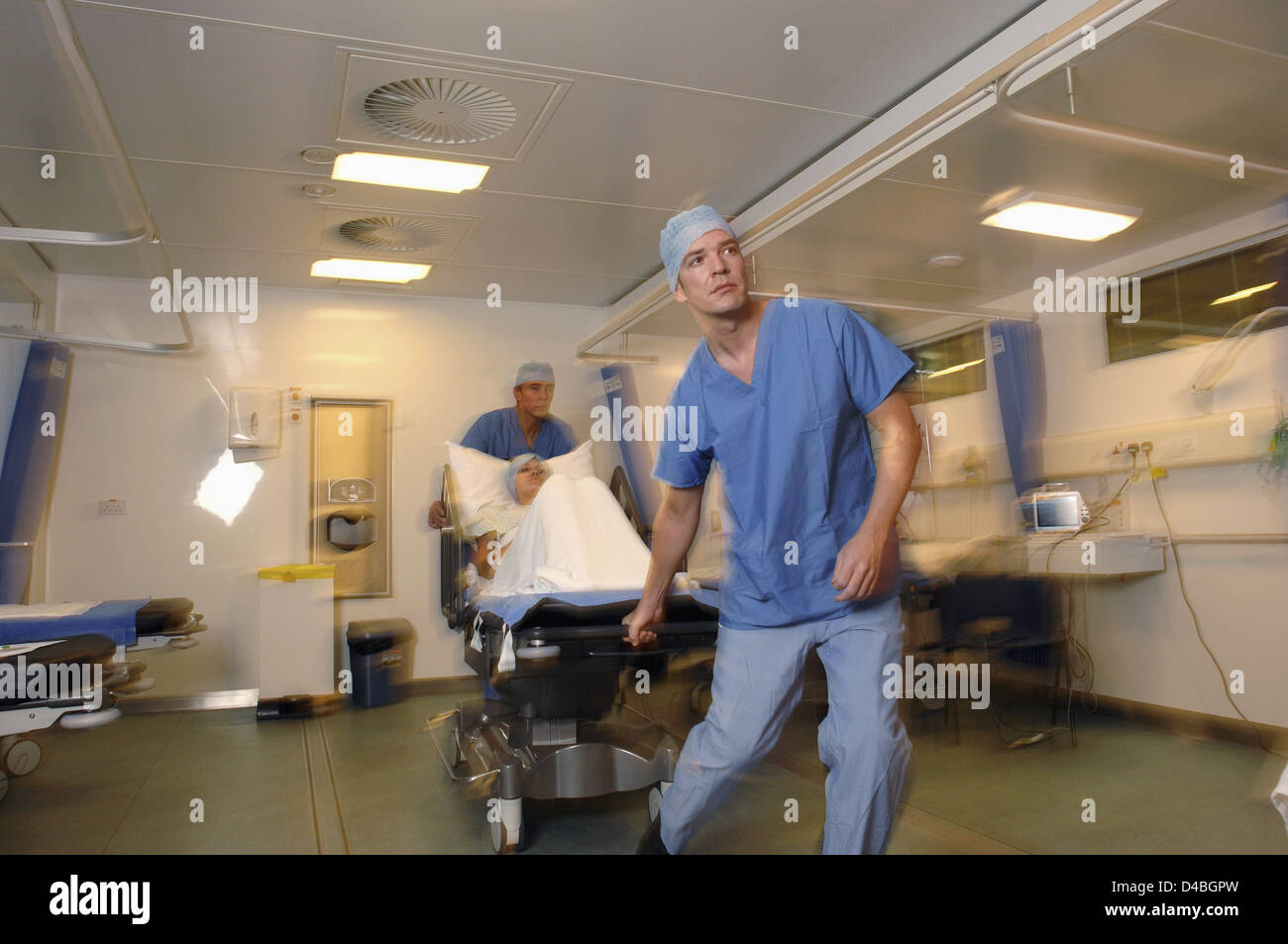 Two hospital porters wheeling patient on trolley bed to operating ...