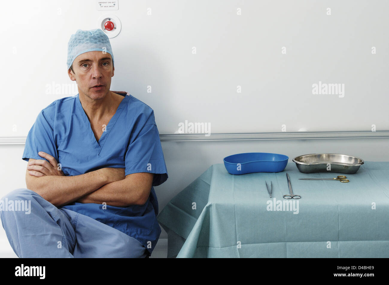 Surgeon in operating theatre relaxing seated next to table with various ...