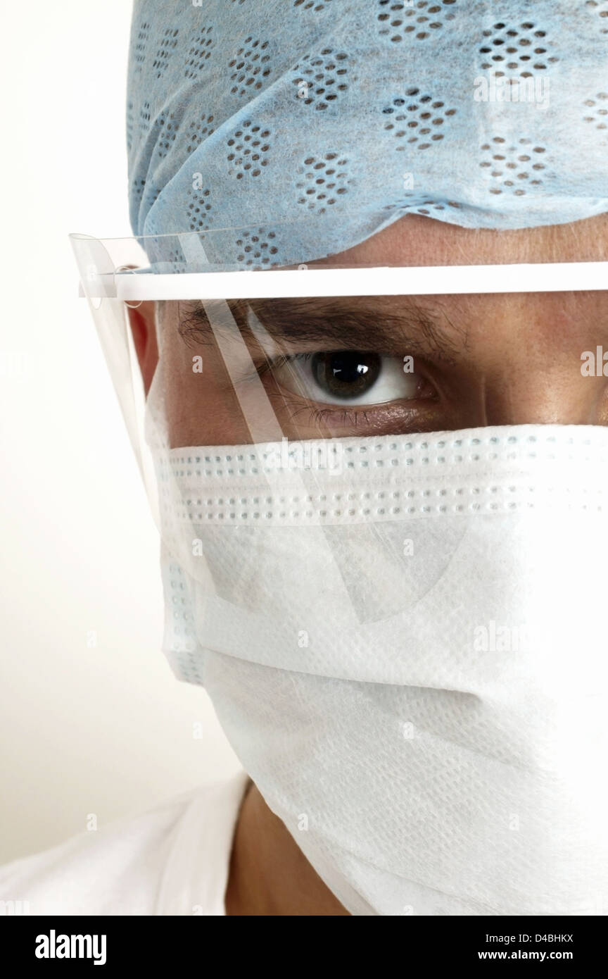 Close-up of young doctor wearing blue surgical cap, white hygiene mask ...