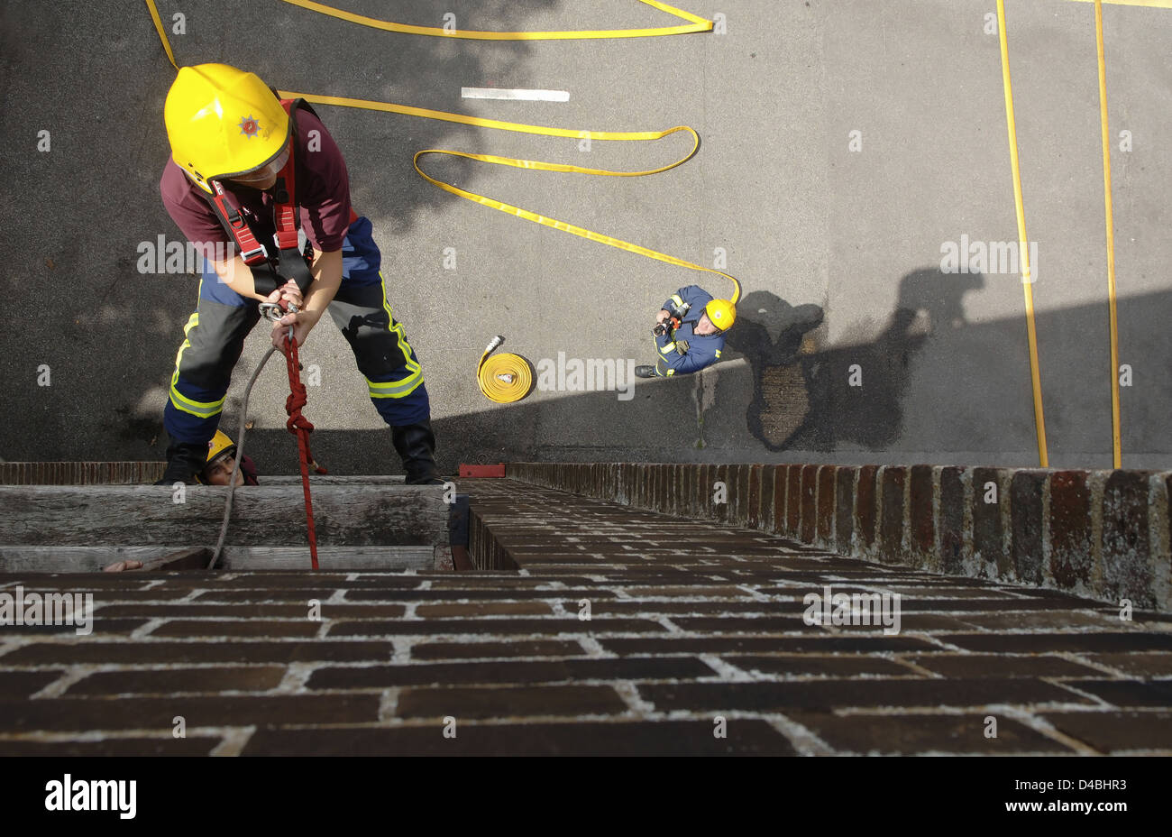 A firefighter climbing rope up side building on training exercise ...