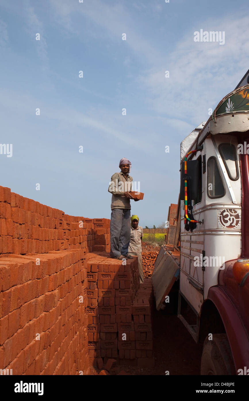 Two men loading bricks onto a decorated truck at a traditional Punjabi ...