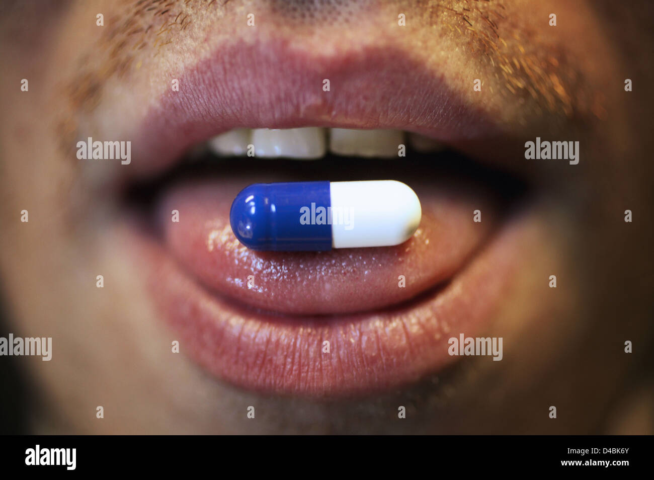 Close-up of blue and white tablet on tongue of young man Stock Photo ...