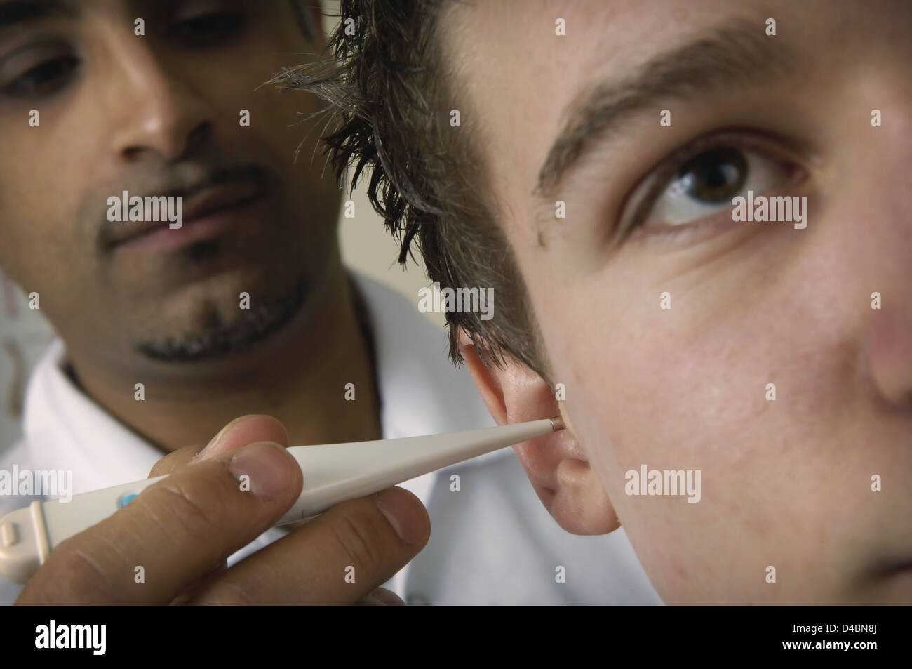 Doctor taking patients aural temperature digital hi-res stock ...