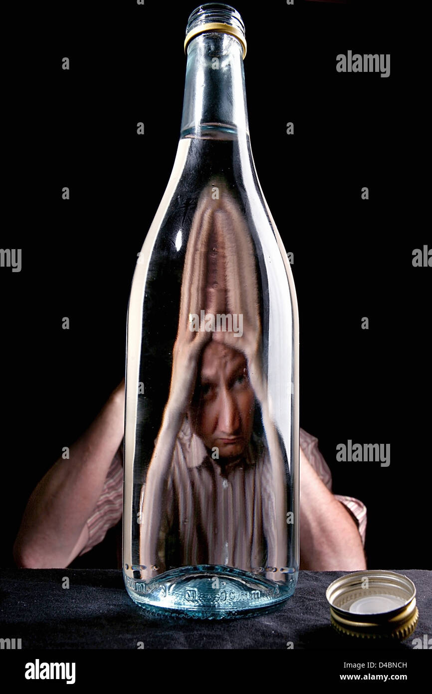 Distorted face of man through empty bottle of alcohol Stock Photo - Alamy