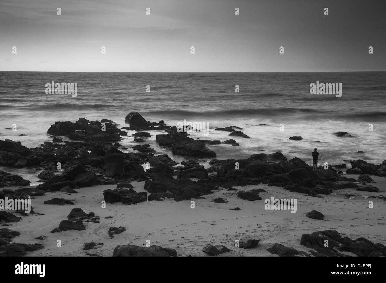 A solitary silhouette of a person, staring into the distance toward the ...