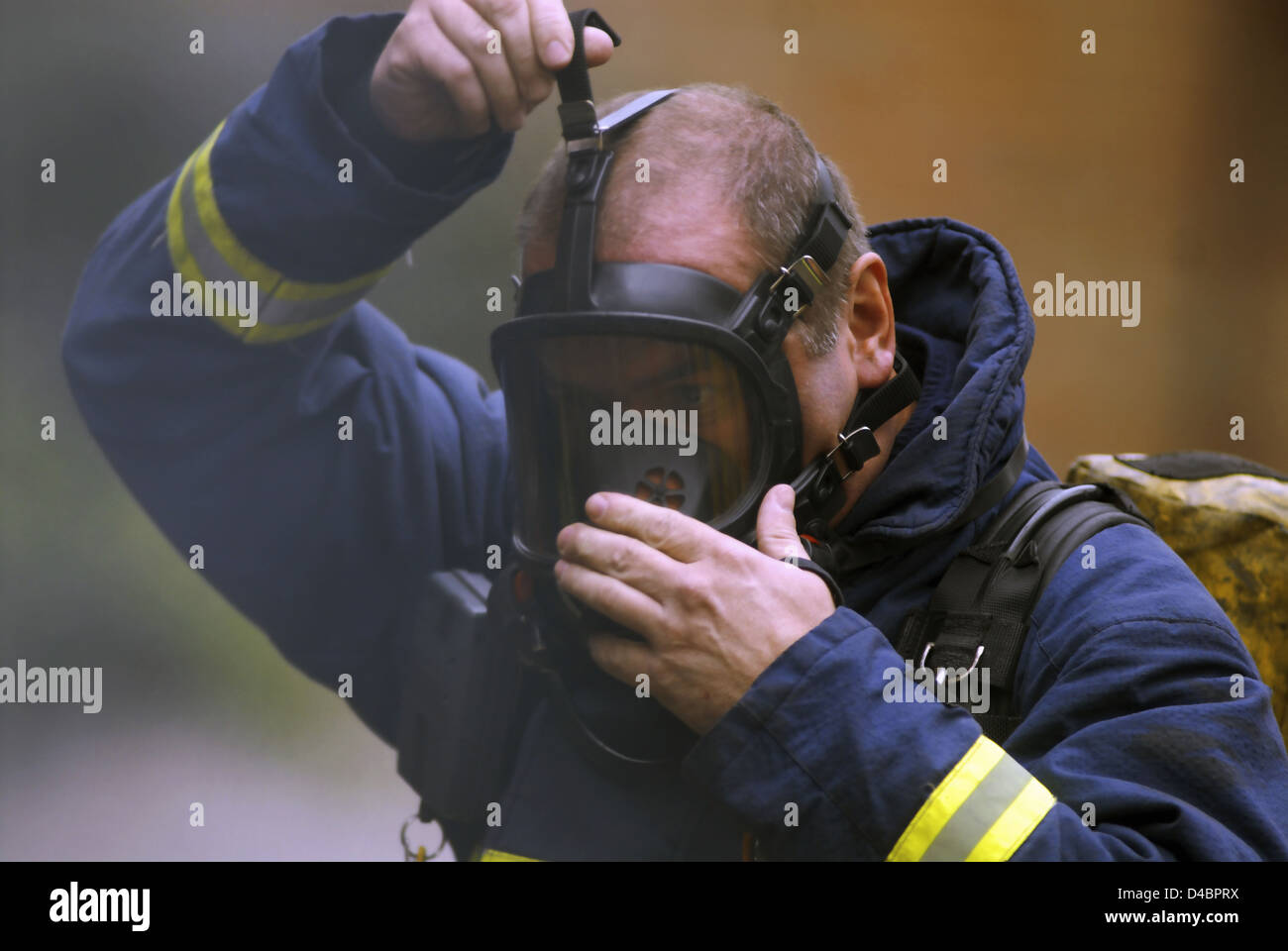 Firefighter putting on gas mask Stock Photo - Alamy