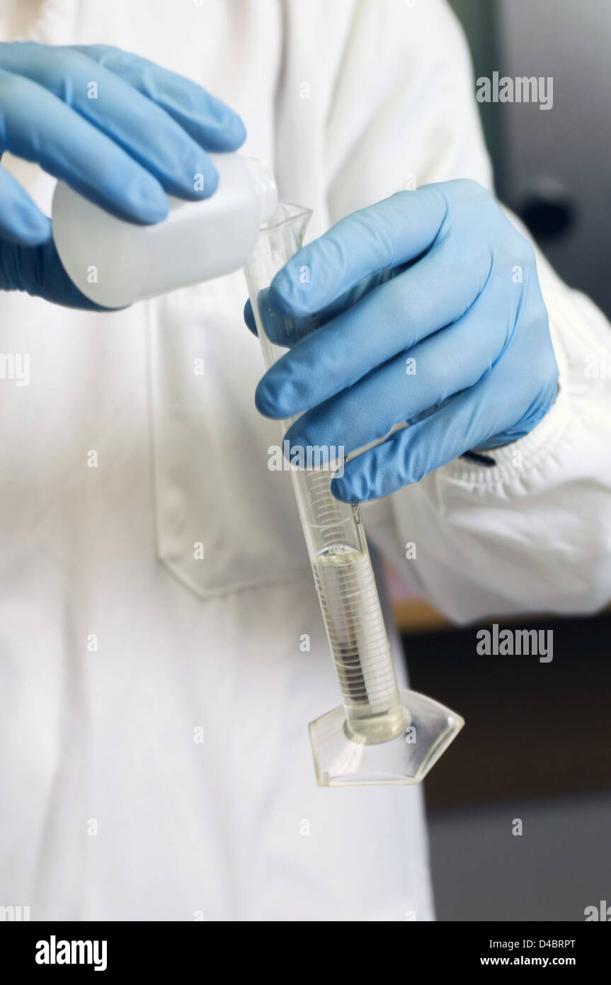 Scientists hands pouring clear liquid into test tube Stock Photo - Alamy