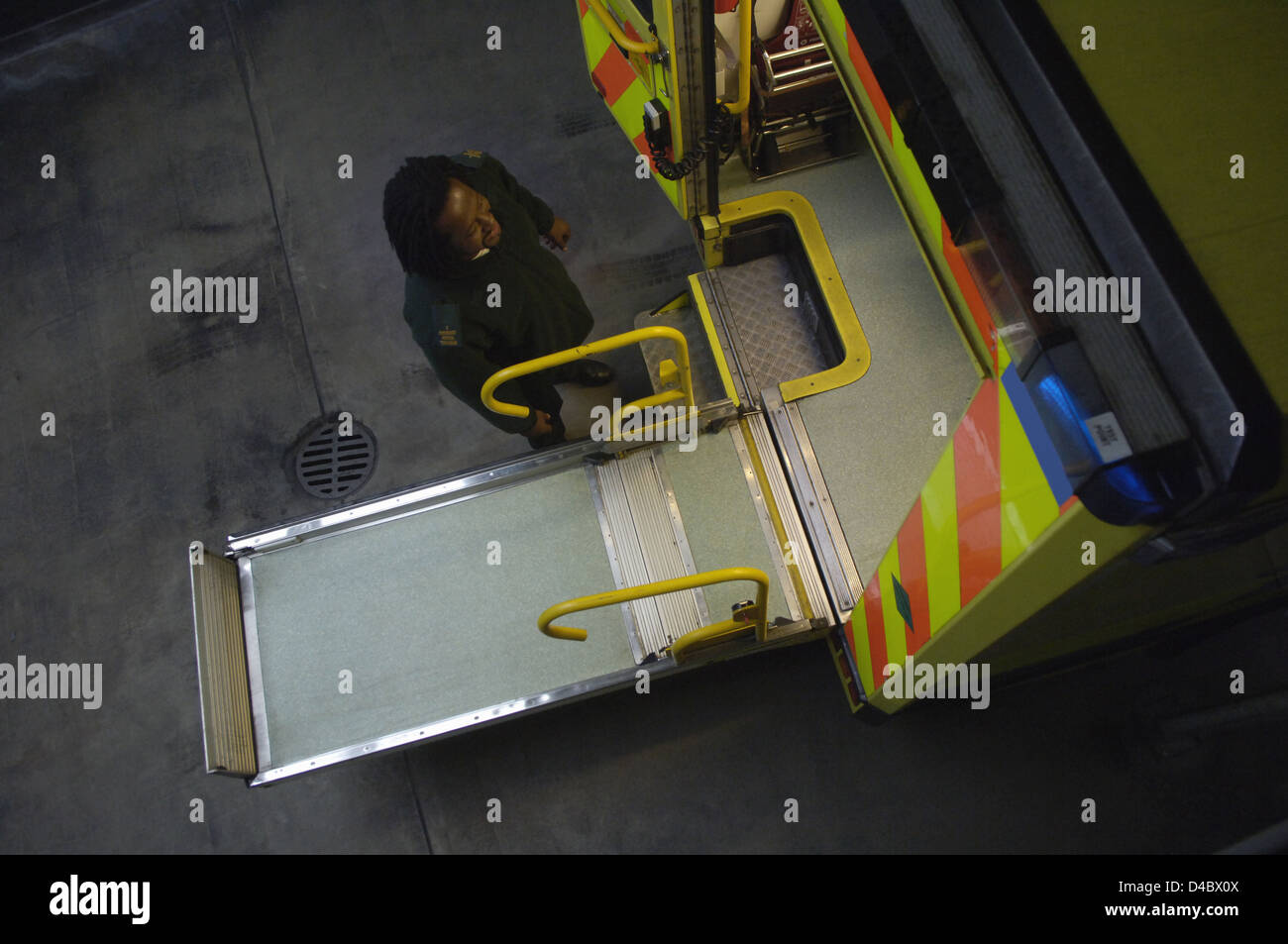 UK, London, ambulance technician unloading wheelchair ramp of ambulance ...