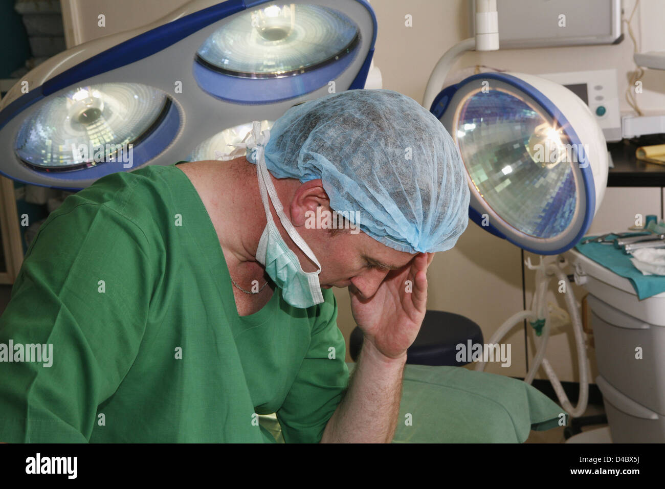 Stressed surgeon holding head in hand Stock Photo - Alamy