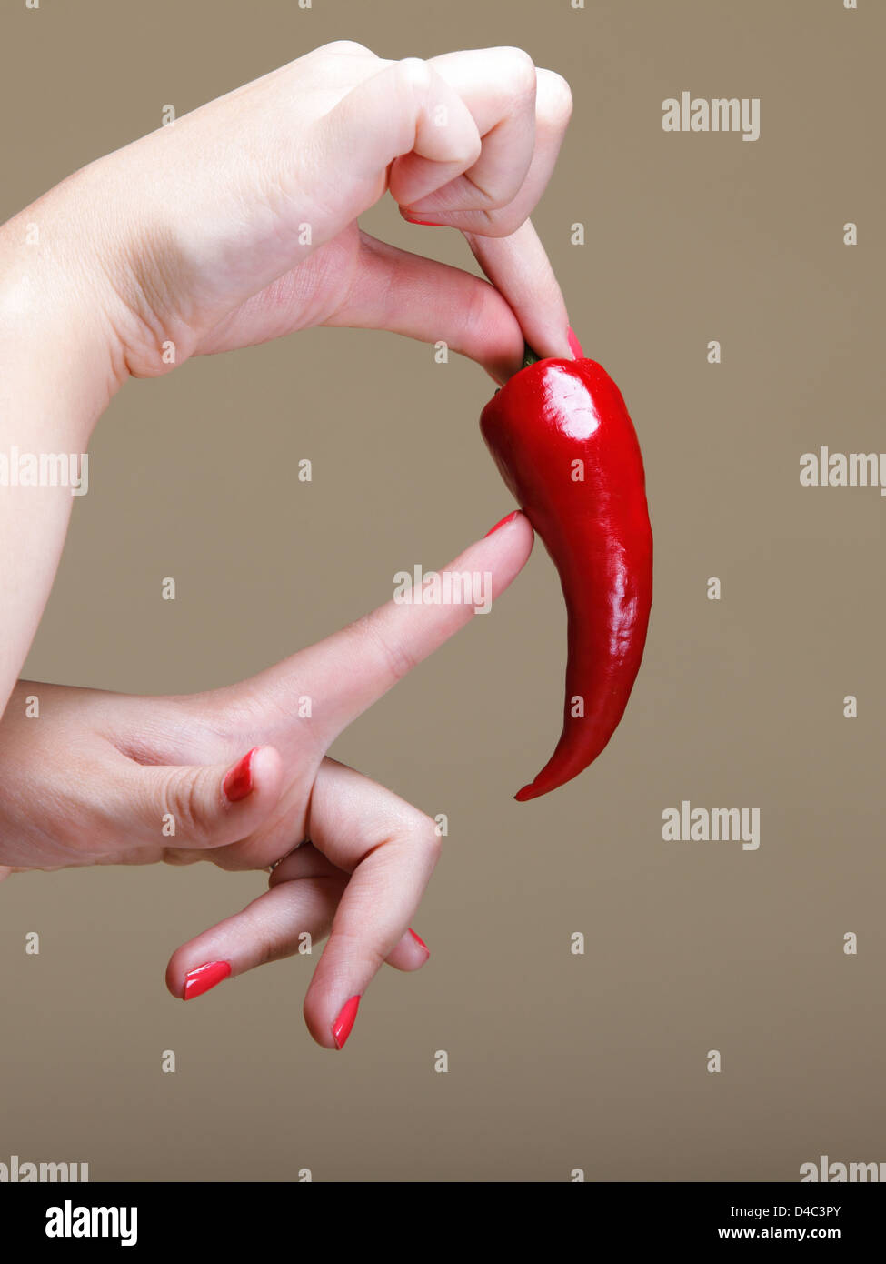 chili pepper in female hand brown background Stock Photo - Alamy