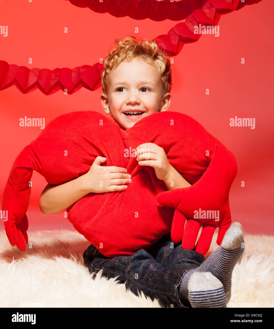 little blond boy hugging heart pillow expressing his love before ...
