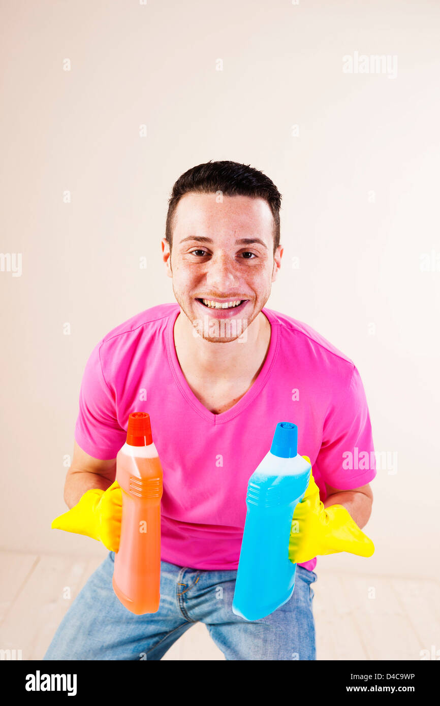 Happy young man holding cleaning agents Stock Photo - Alamy