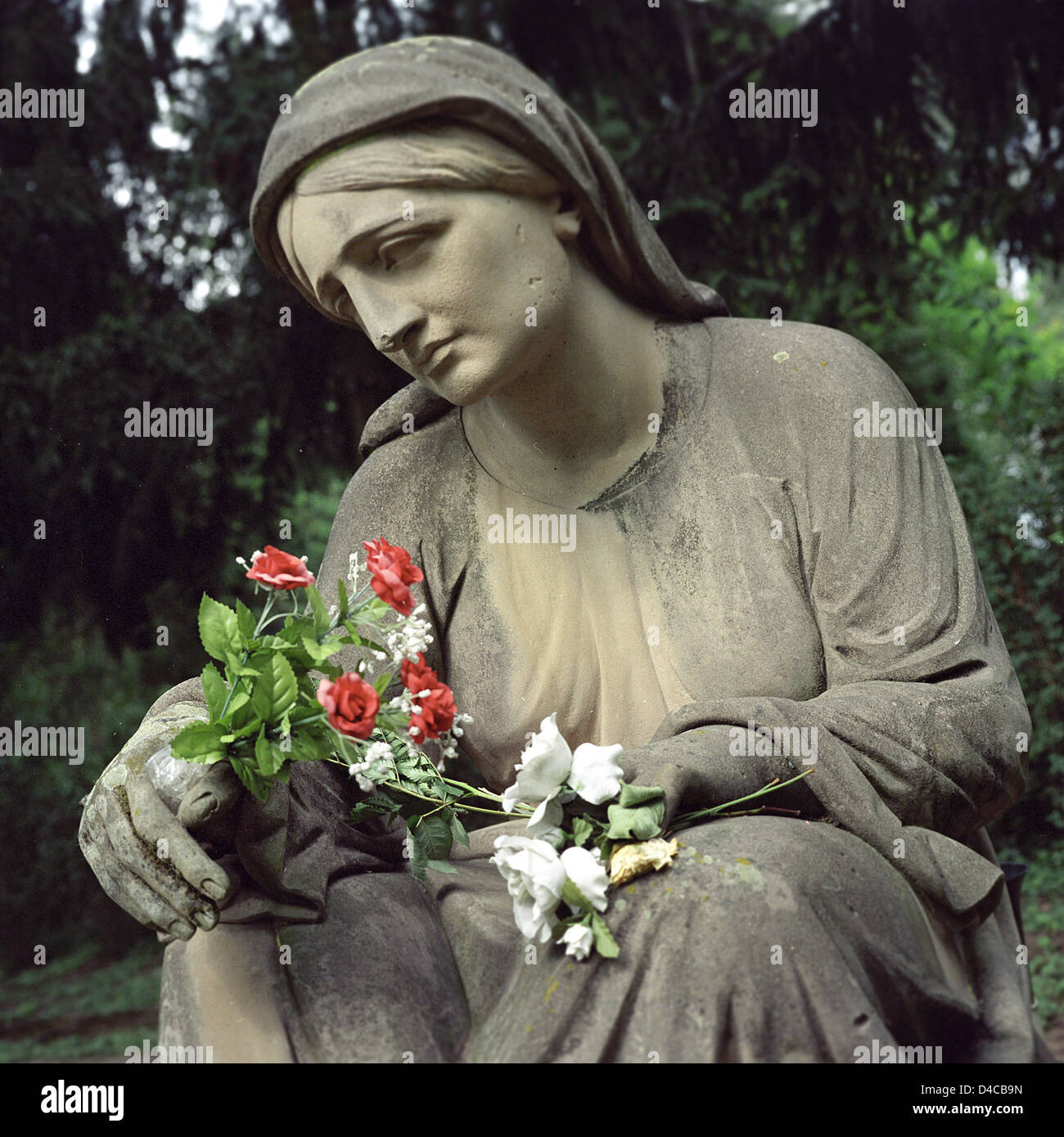 The statue of a mourning woman, holding plastic flowers in her hands ...