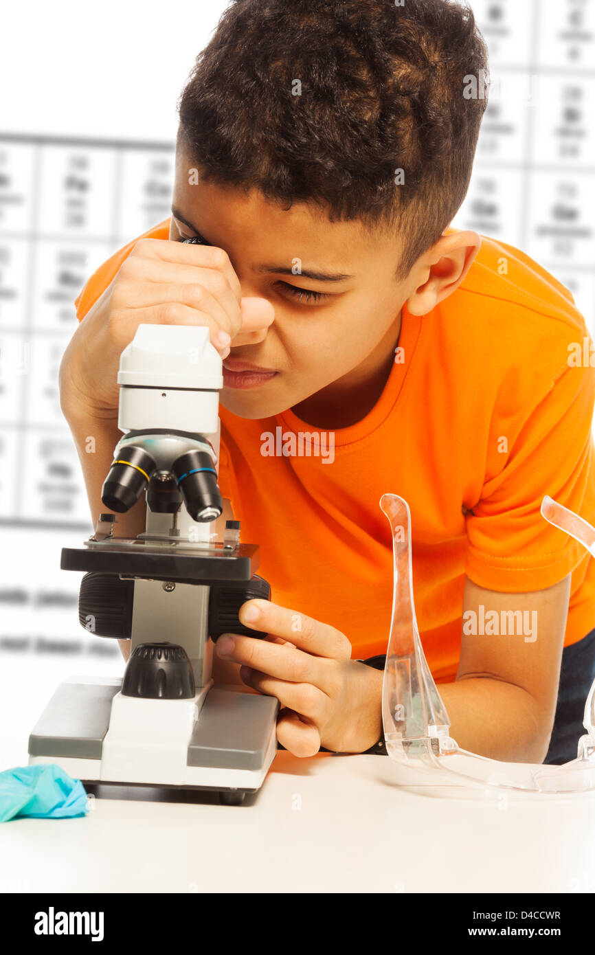 Black boy in orange looking in microscope on biology lesson Stock Photo ...