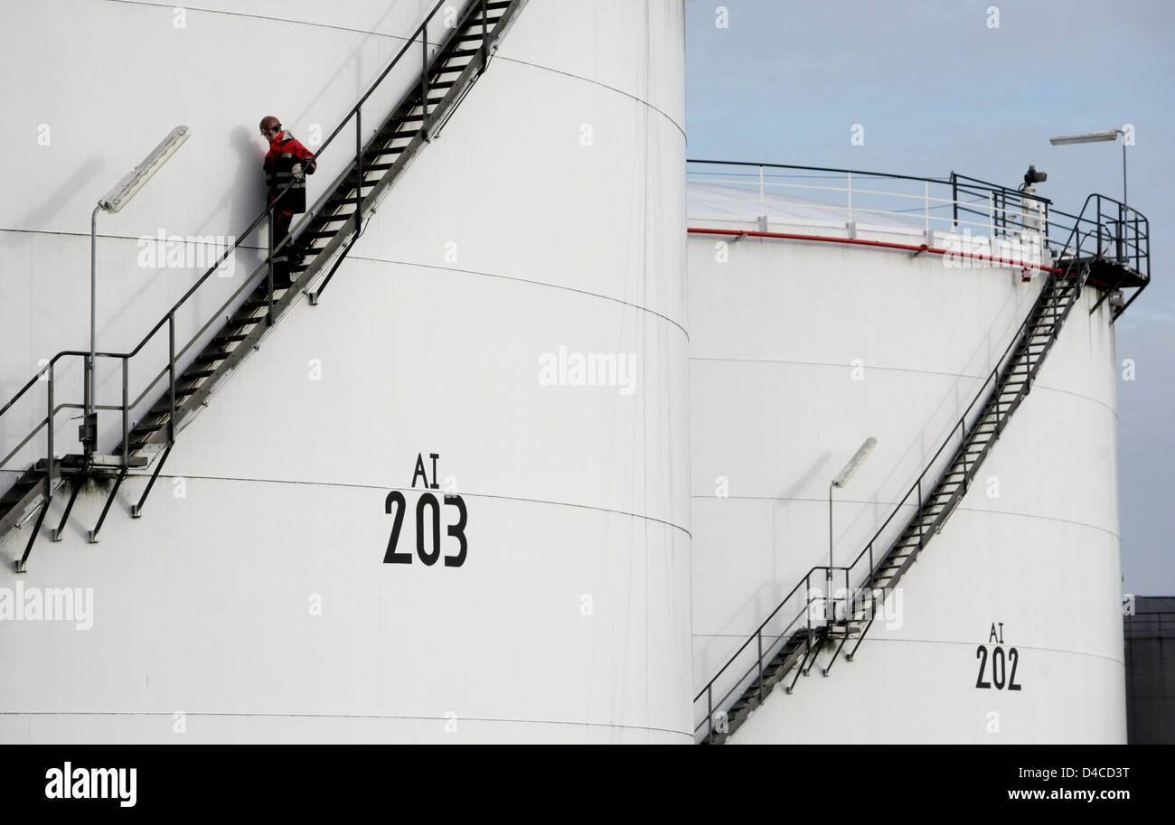 A worker descends a ladder at at huge tanks with fuel pictured on the ...