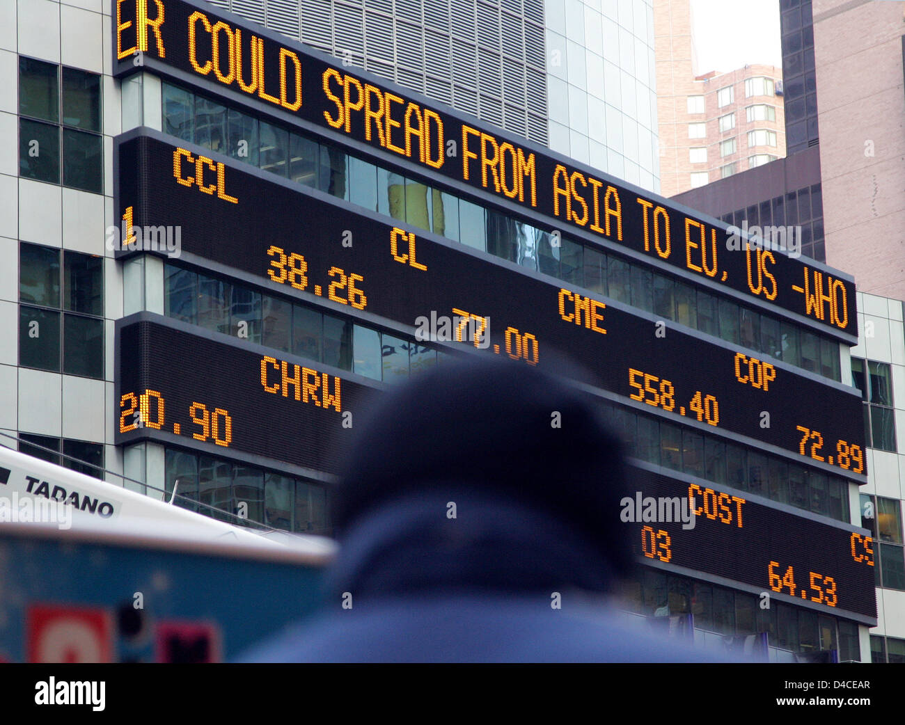 A passer-by has a look at the stock prizes displayed at Times Square in ...