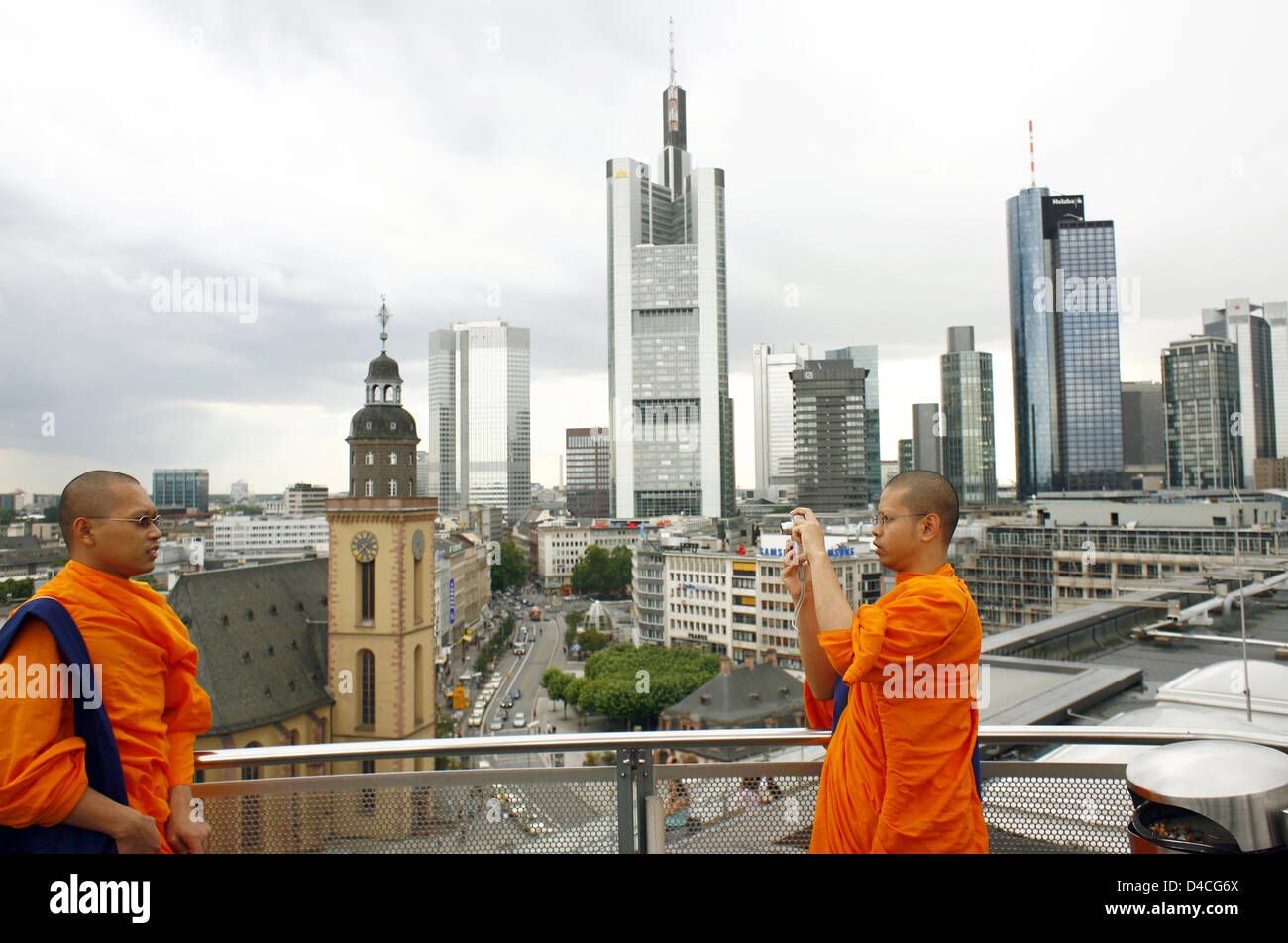 (dpa file) Buddhist monks take pictures in front of the skyline of ...