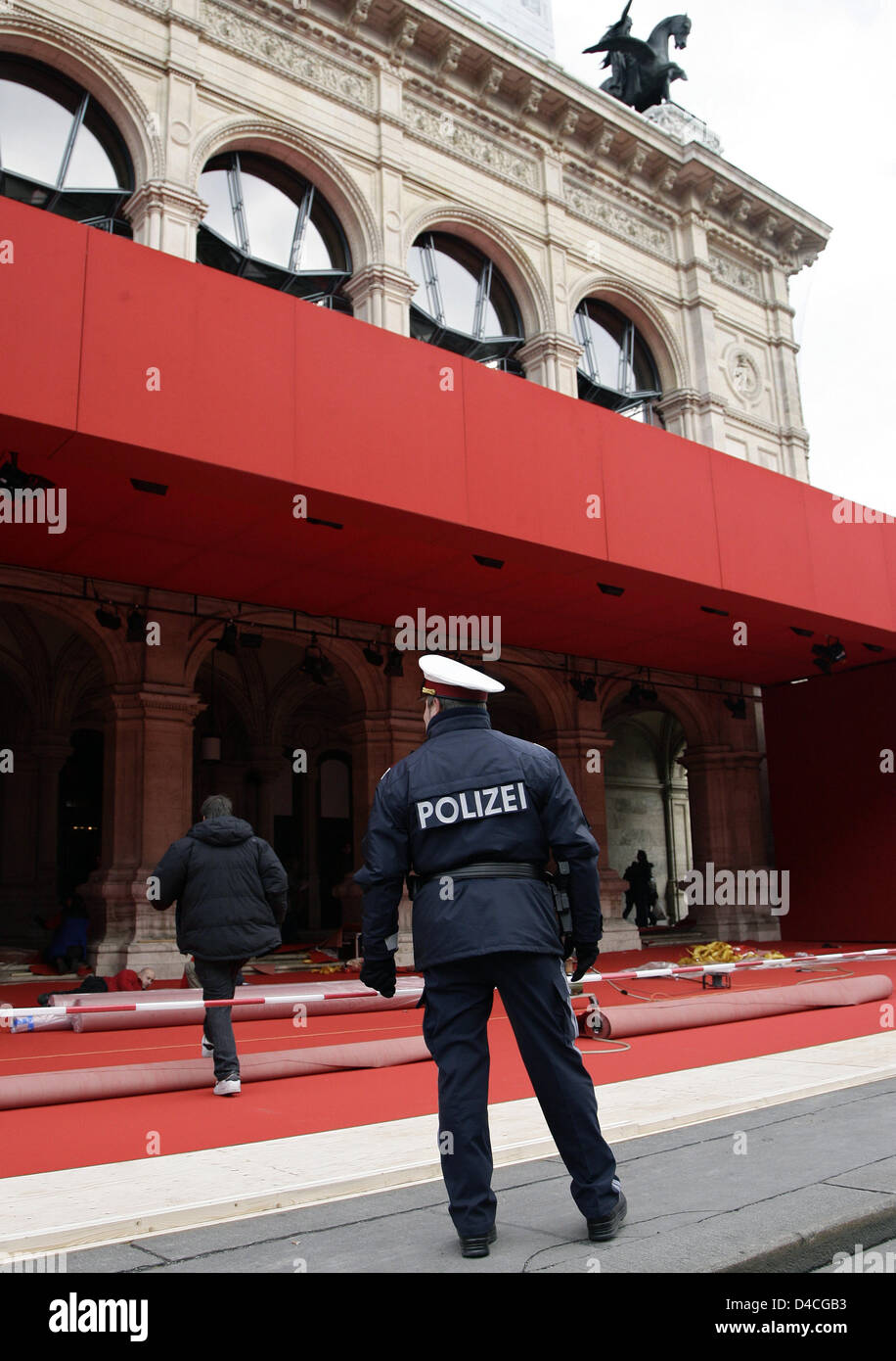 A police officer supervises the preperations of the red carpet for the ...