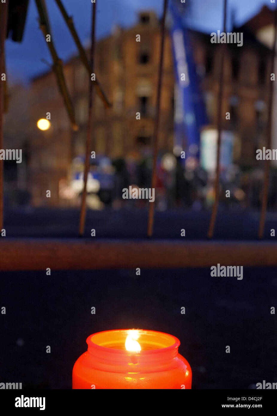 A candle burns in front of a burnt out residential house in ...