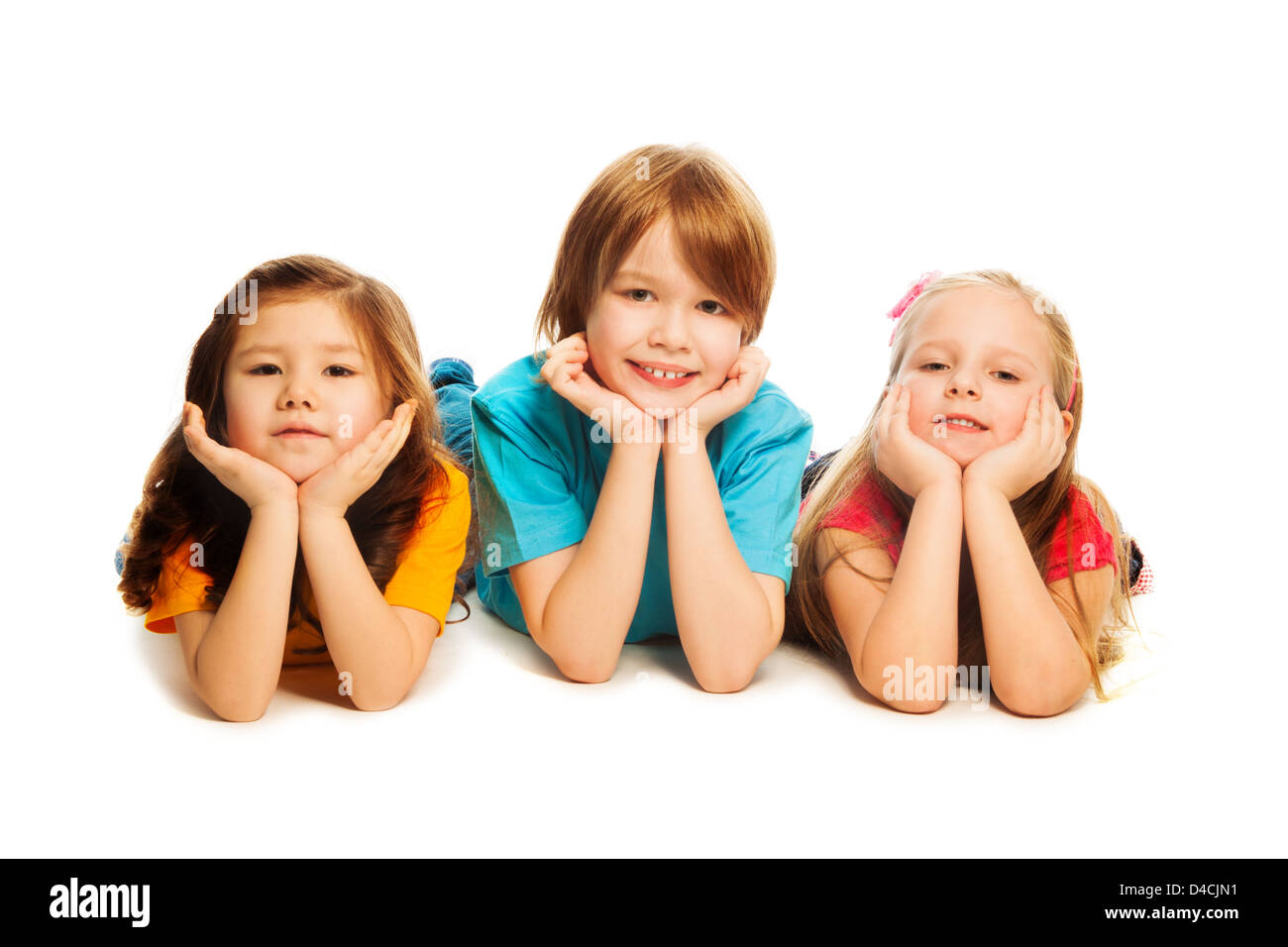 Three happy kids laying on the floor in a line together with hands ...
