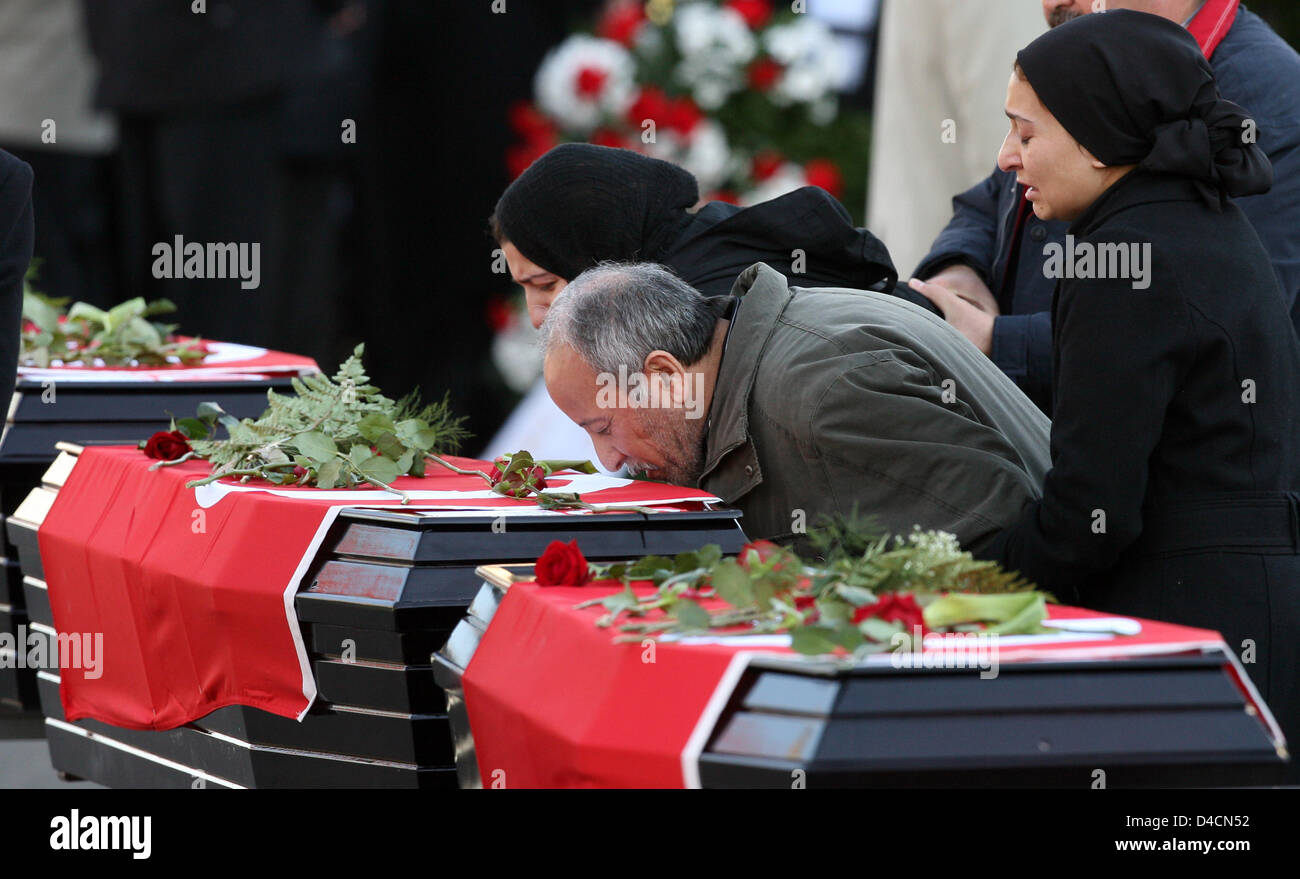 The bereaved cry over the coffins of their dead relatives during a ...