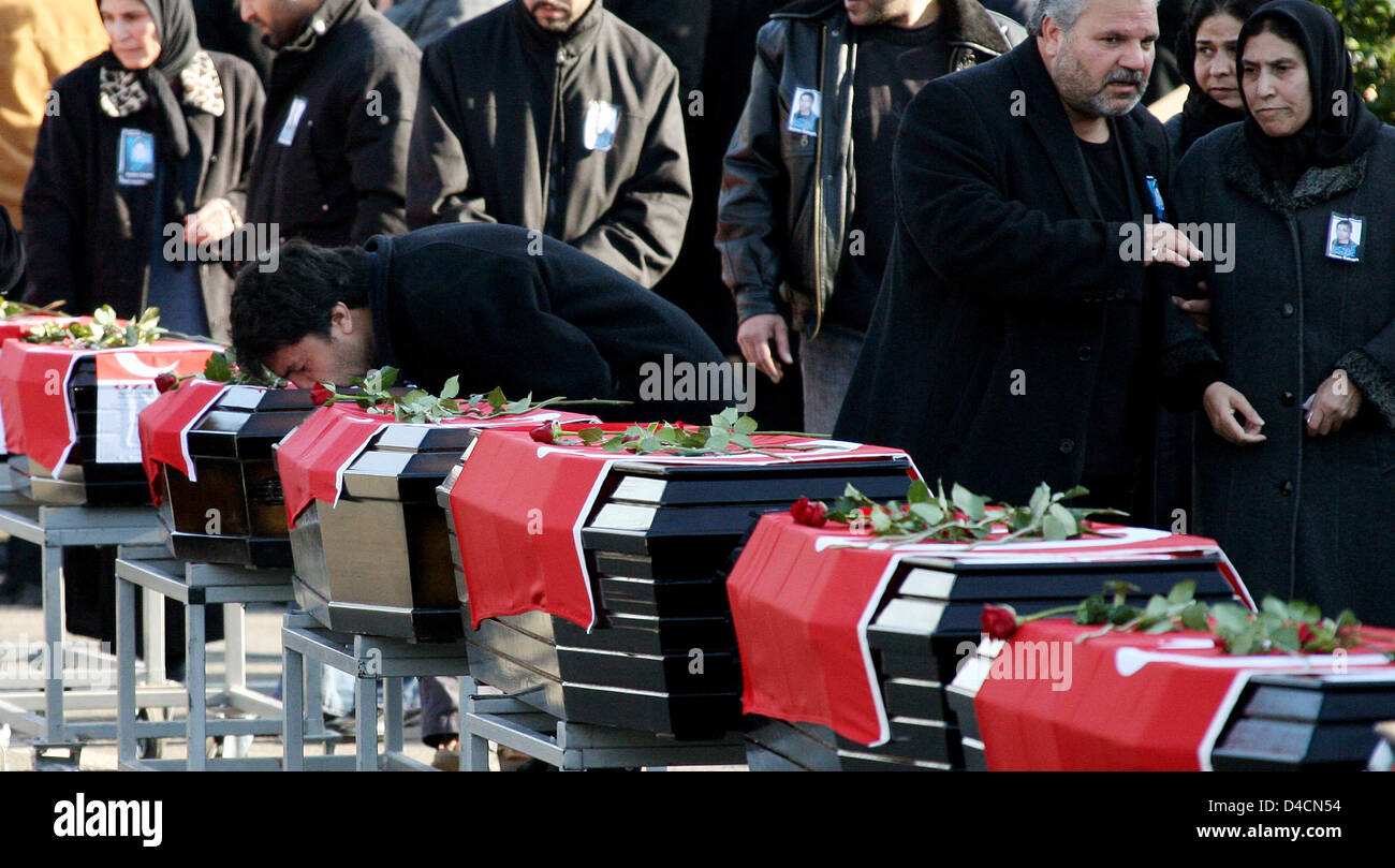 The bereaved cry over the coffins of their dead relatives during a ...