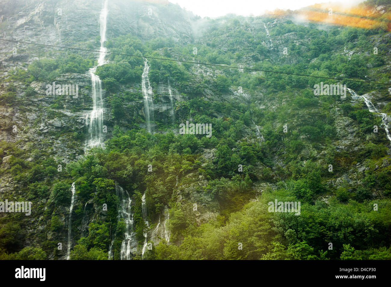Cascading waterfalls down a forest rock wall Stock Photo - Alamy