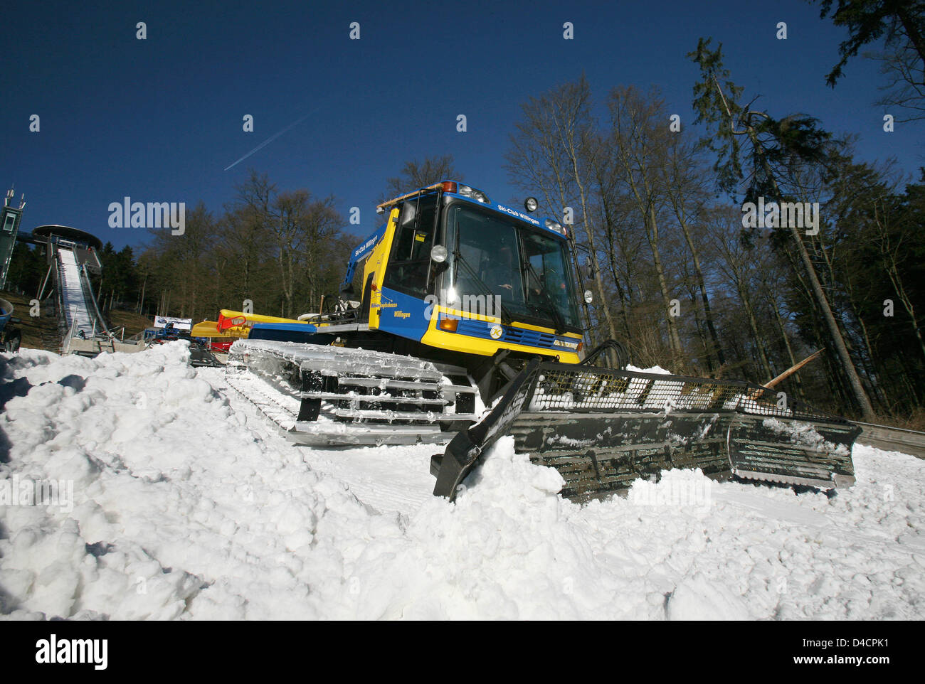 A slope bulldozer spreads the snow on the the jumping hill of the ...