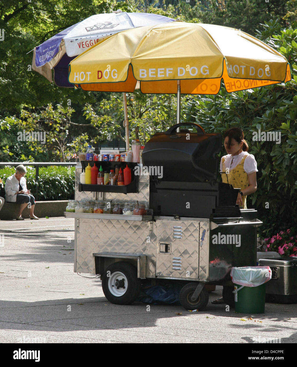 The picture shows a woman selling hot dogs from a booth in Vancouver ...