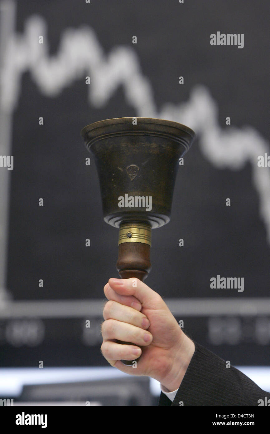 A hand rings the traditional stock exchange bell in a posed scene in ...