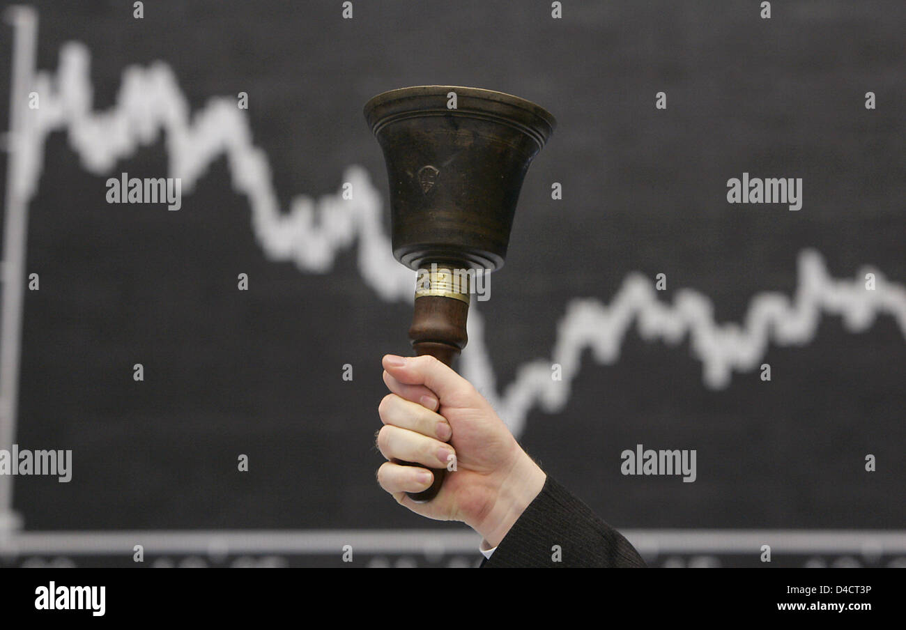 A hand rings the traditional stock exchange bell in a posed scene in ...