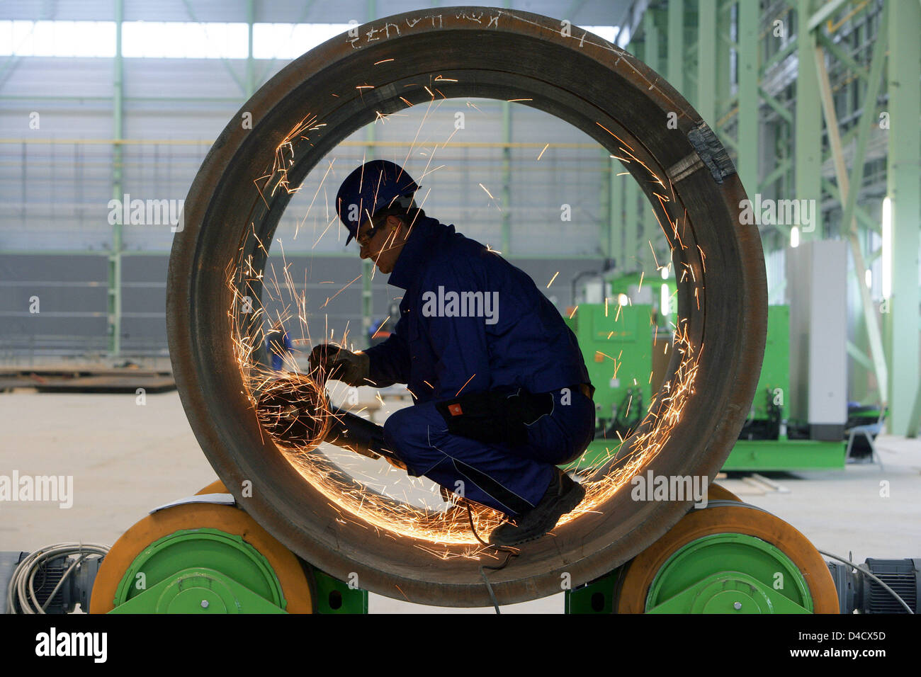 An employee of EEW Special Pipe Constructions Rostock grinds a weld ...