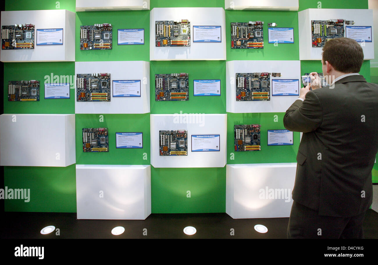 A visitor takes a picture of an exhibition of motherboards at the stand ...