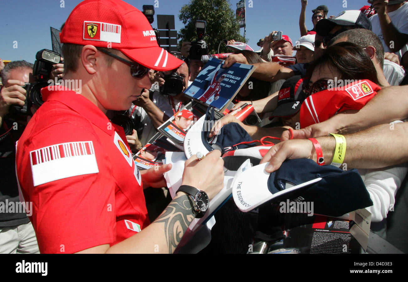 Finnish Formula One driver Kimi Raikkonen (L) of Ferrari team signes ...