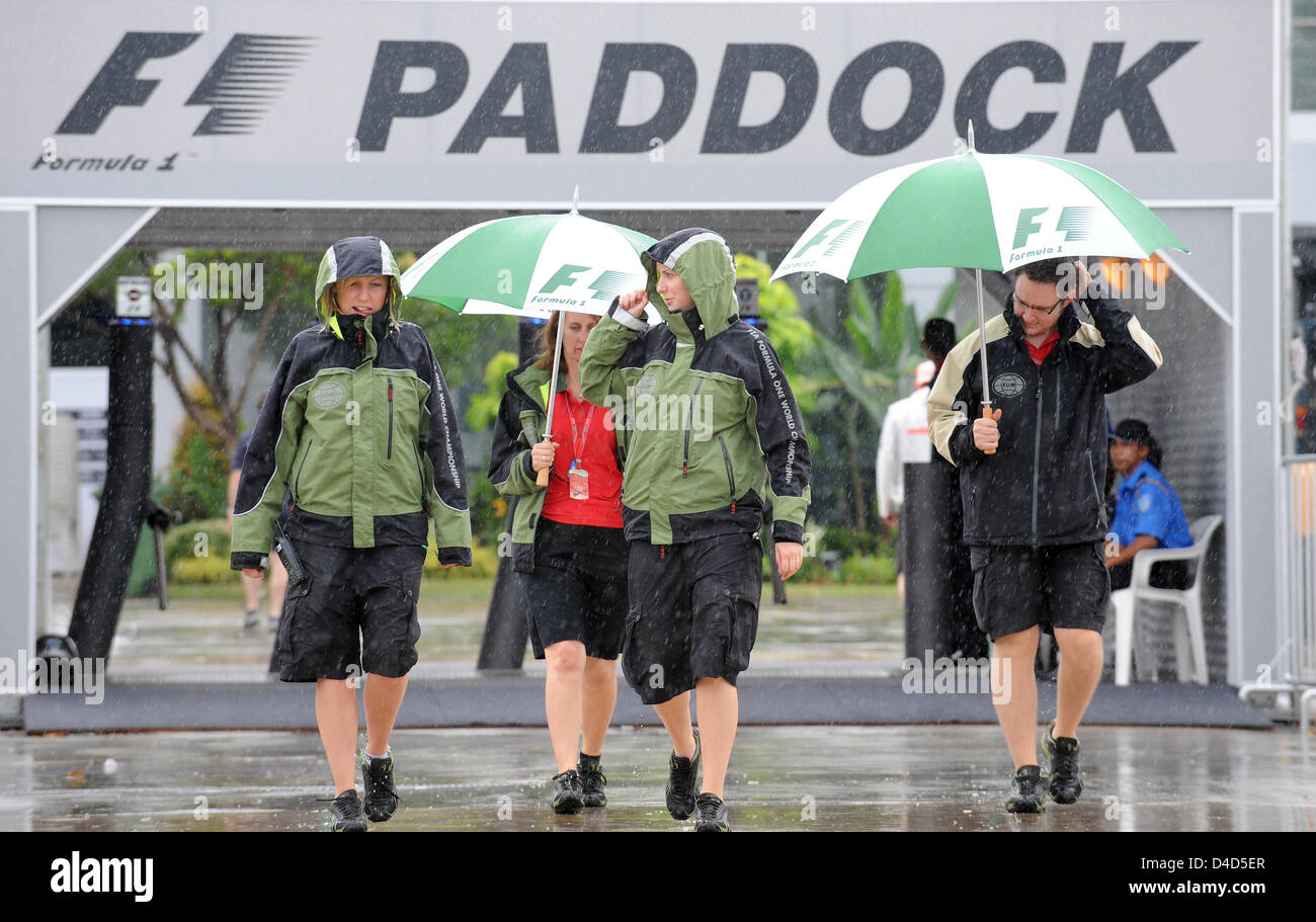 Formula One personnel with umbrellas leave the paddock at the Sepang ...