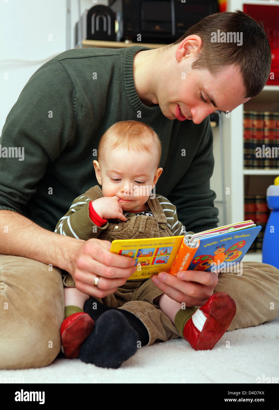 Bjoern Gerth looks through a childrens book with his son at his home in ...