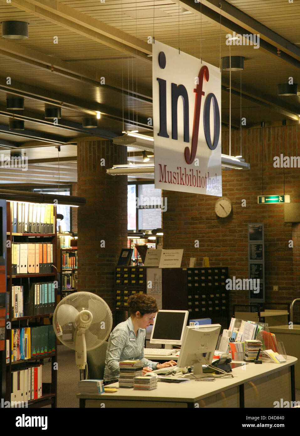 A library employee sits at the information desk at the music section of ...