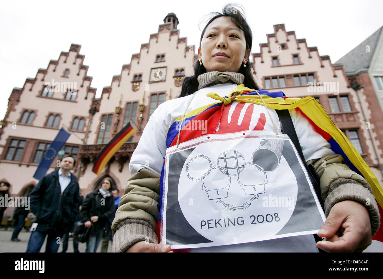 A Tibetan woman holds a placard showing the Olympic rings made of ...