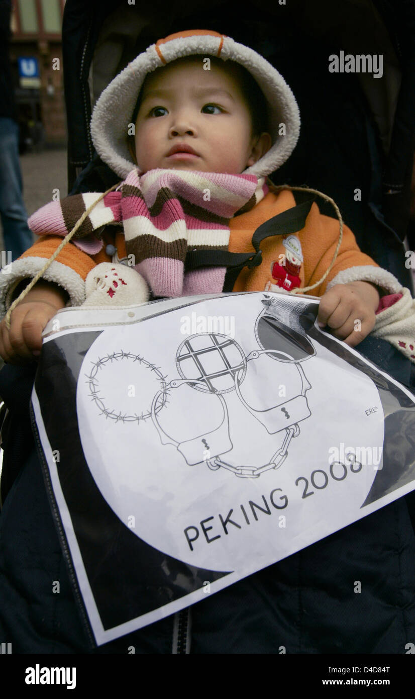 A little Tibetan holds a placard showing the Olympic rings made of ...