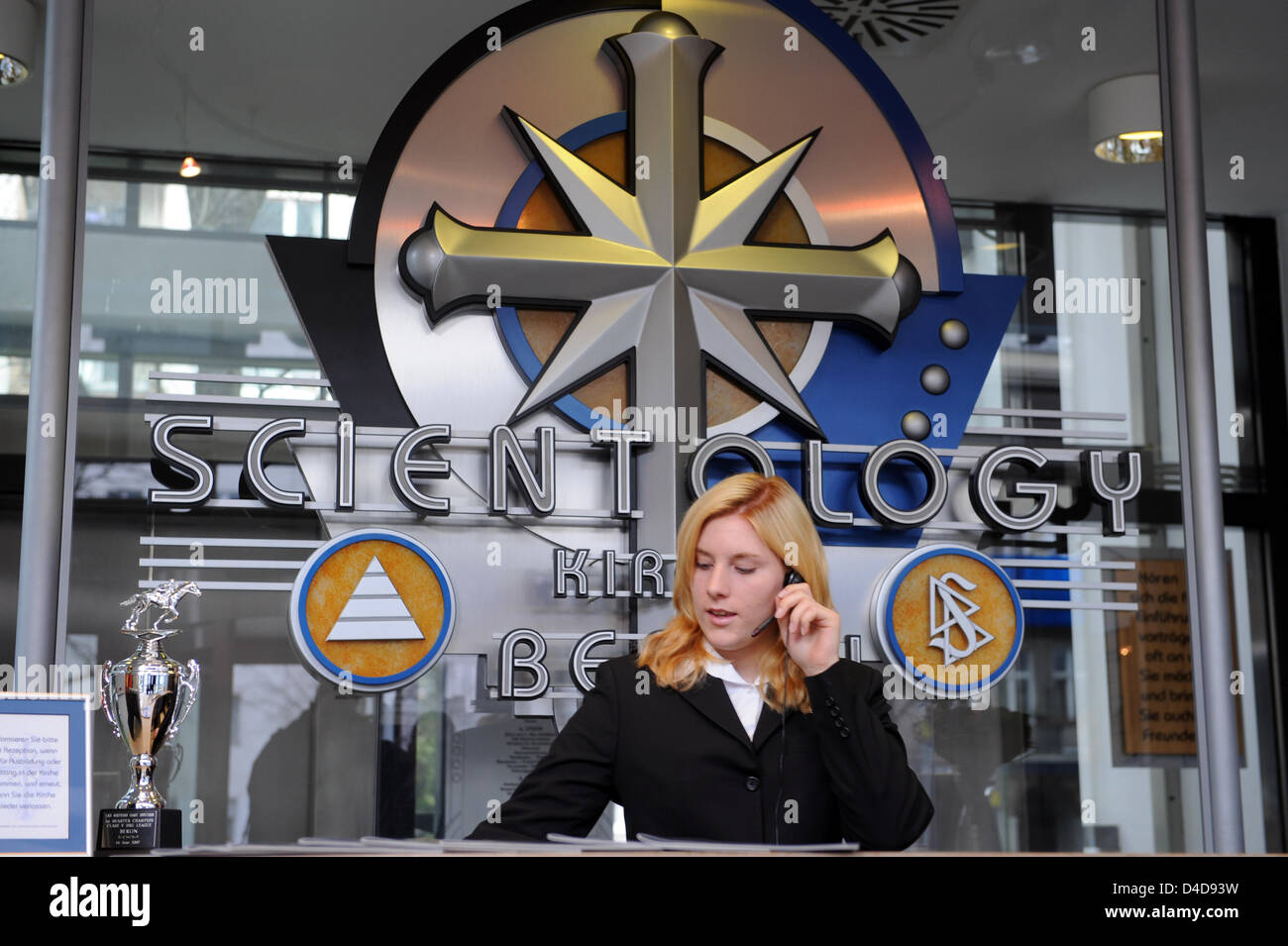 A receptionist makes a call sitting under the logo of Scientology at ...