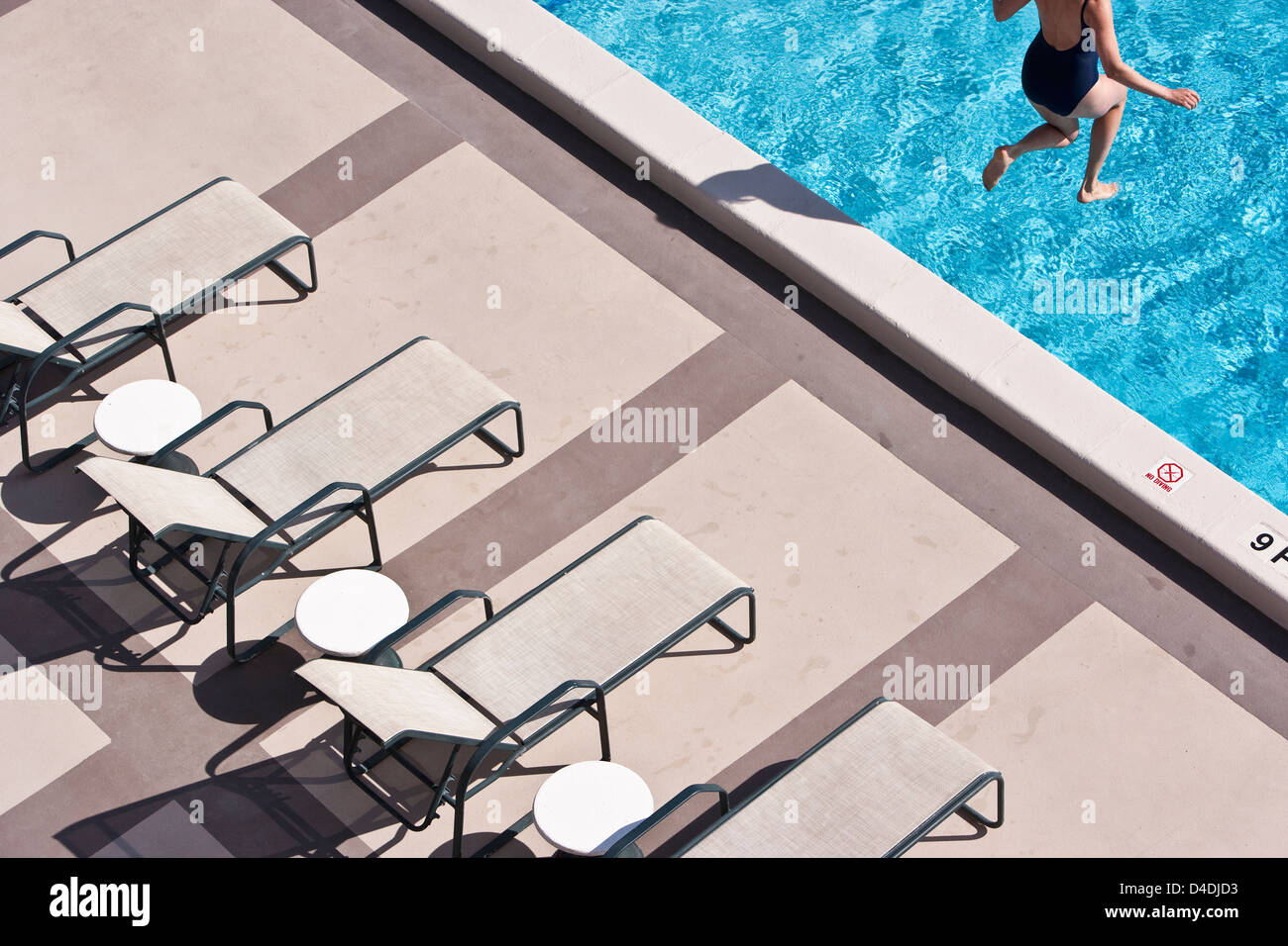 A woman wearing a bathing suit jumping into the deep end of a swimming ...