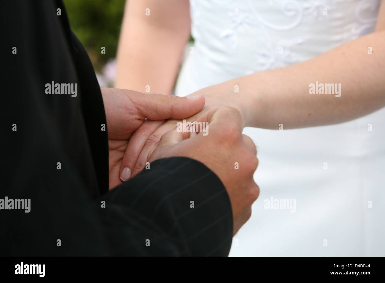 Groom putting wedding ring on bride Stock Photo - Alamy
