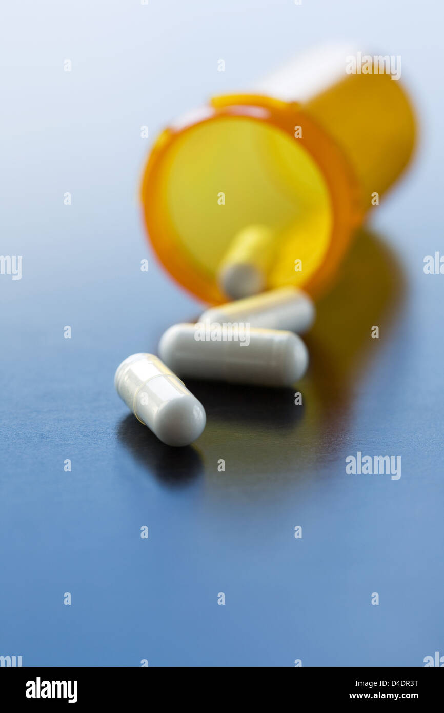 Capsules spilled from pill bottle Stock Photo - Alamy
